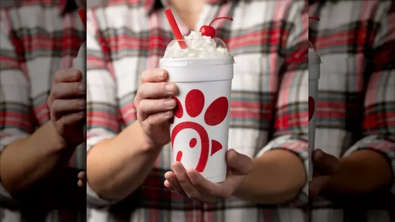 Uomo in flanella che porge il milkshake alla menta piperita di Chick-fil-A