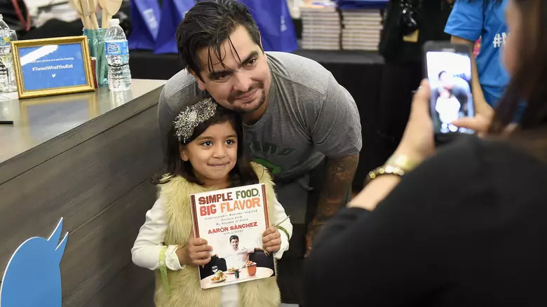 El xef Aaron Sanchez amb un jove fan sostenint un llibre de cuina